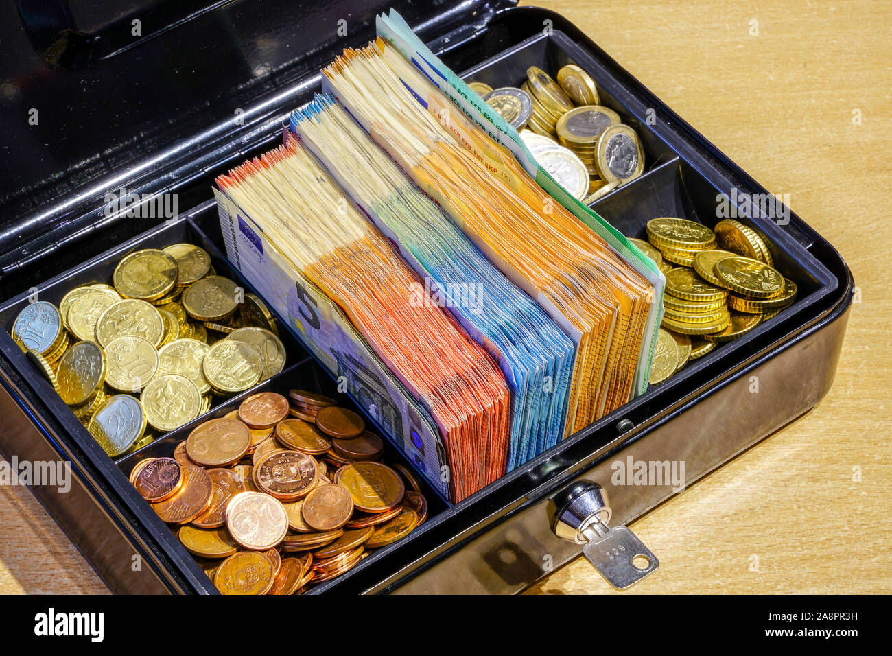 a small cash box full of coins and many banknotes Stock Photo - Alamy