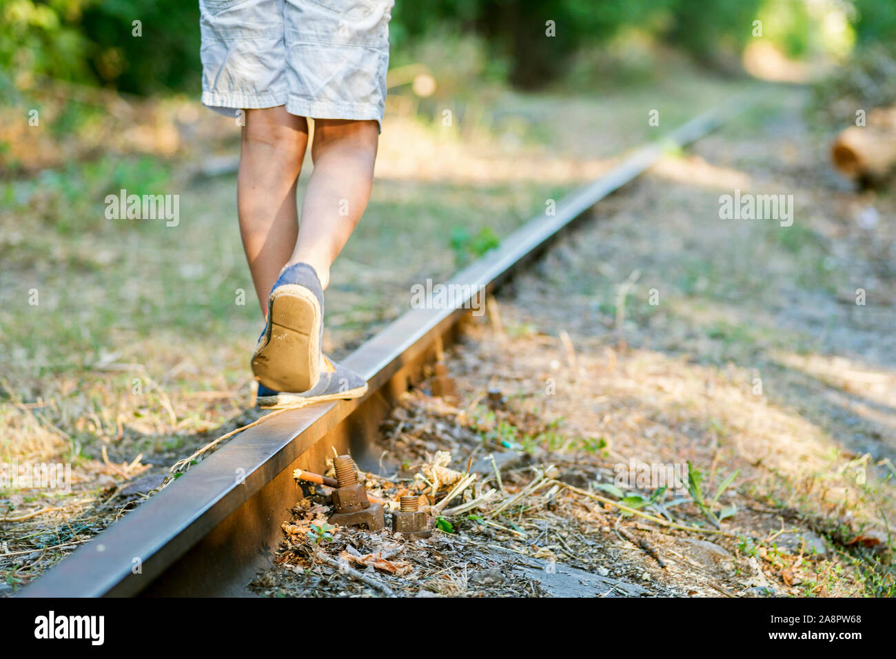 Little boy steps on the rails of the railway, being exposed to danger ...