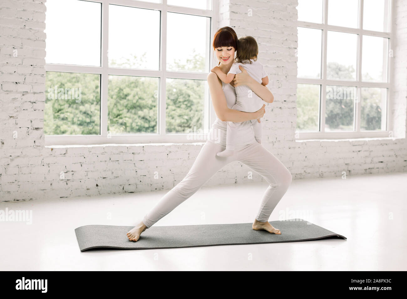 young mother does physical yoga exercises together with her baby. mother with baby doing ...