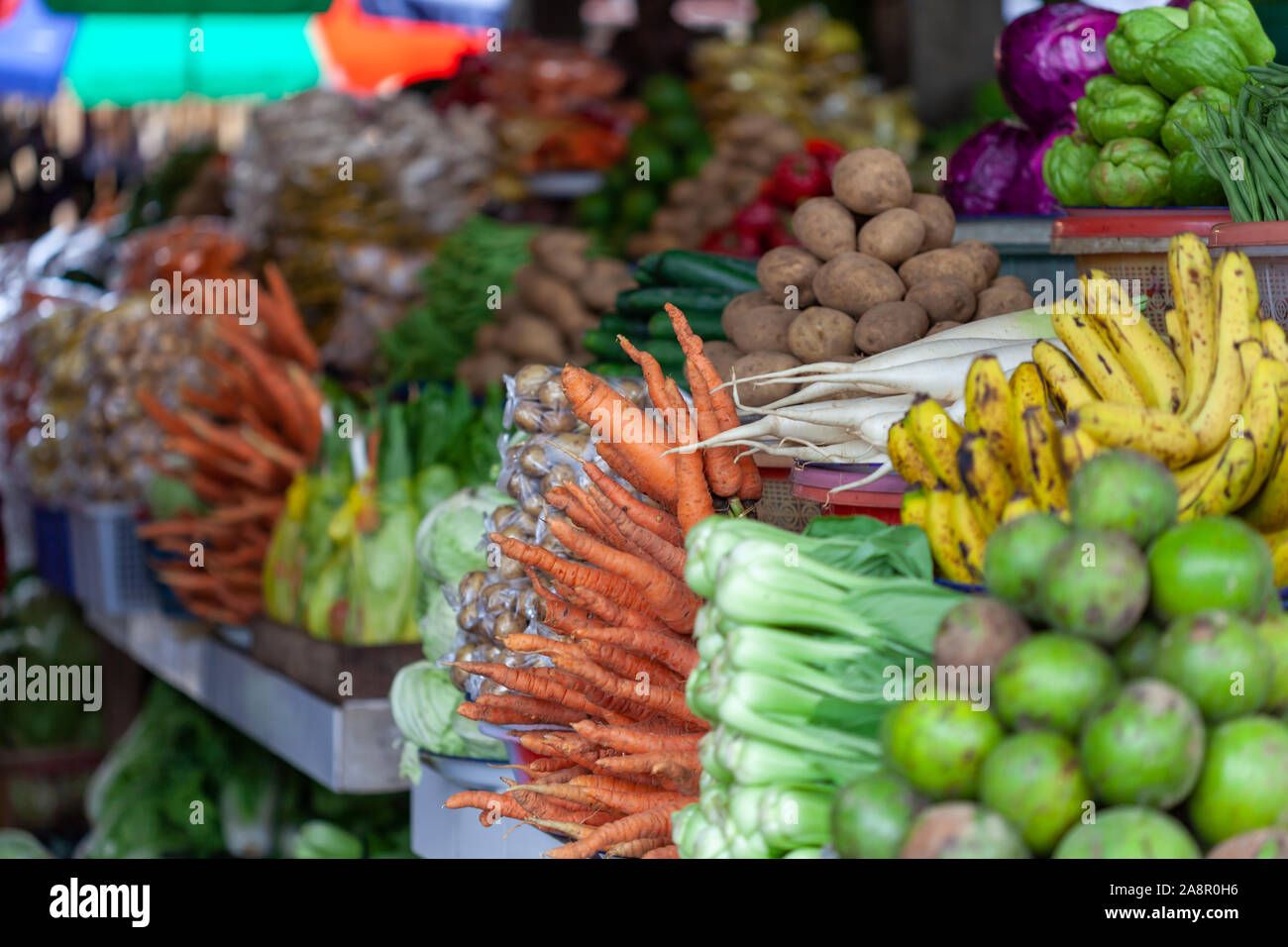 Vegetable market scene, carrots, potatoes, pak choi, limes, bananas. a ...