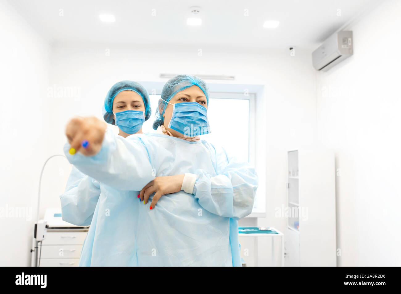 A nurse dresses a surgeon in a sterile suit before surgery Stock Photo ...