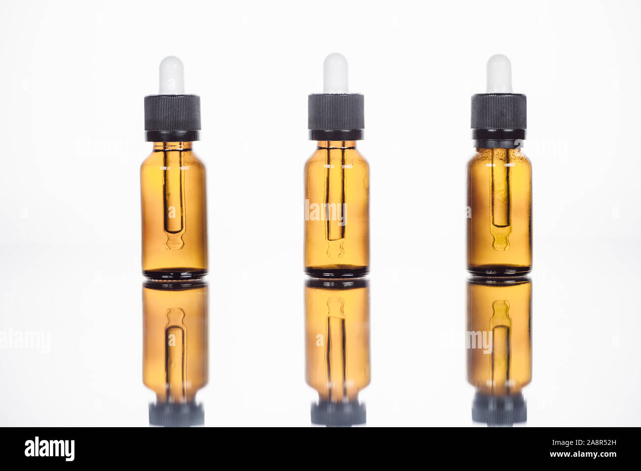 bottles of natural serum on surface with reflection isolated on white ...