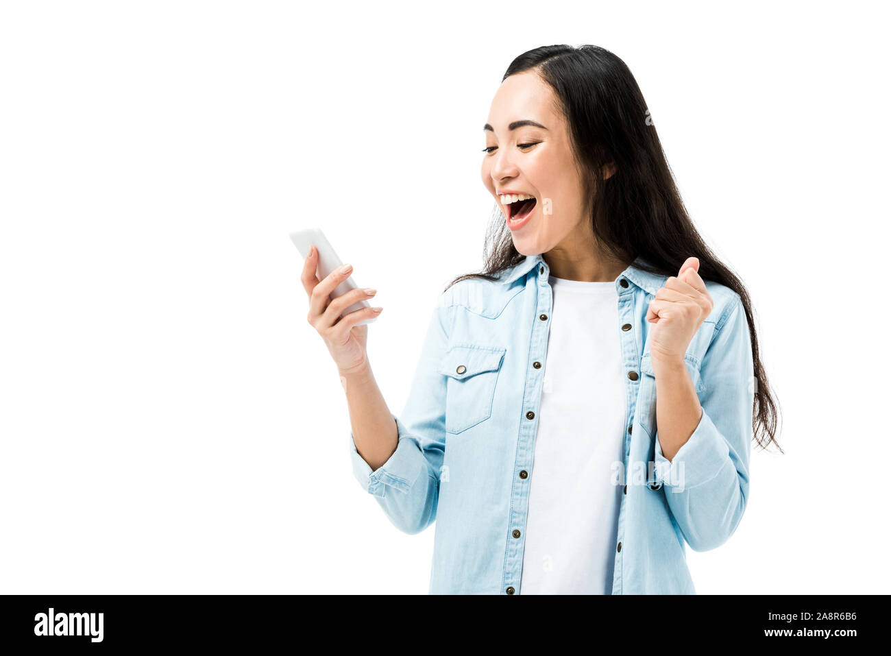 attractive and smiling asian woman in denim shirt holding smartphone ...