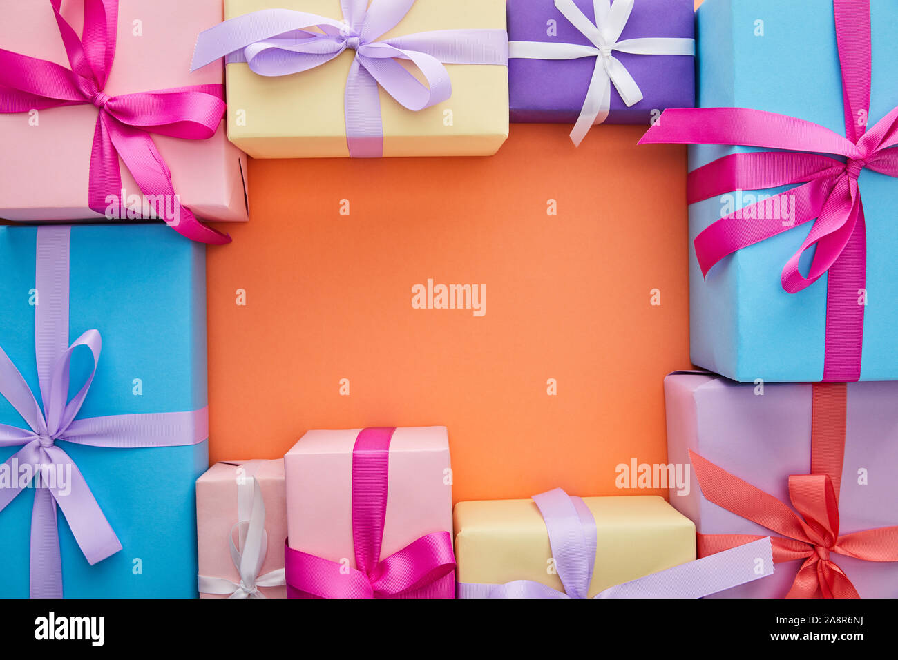square frame of multicolored gift boxes with ribbons and bows on orange ...