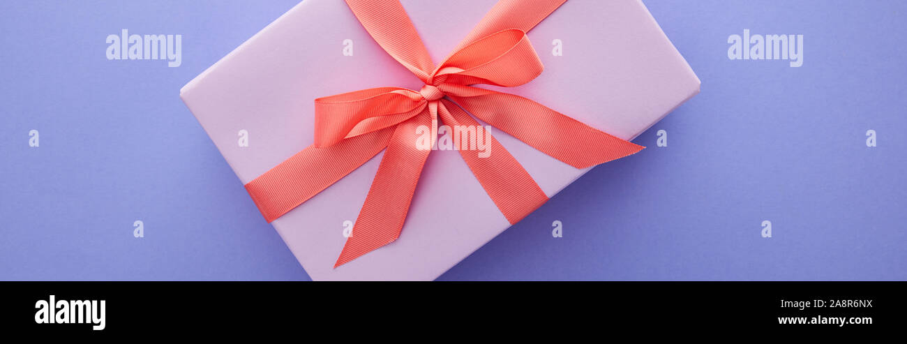 top view of violet gift box with red ribbon and bow on purple ...