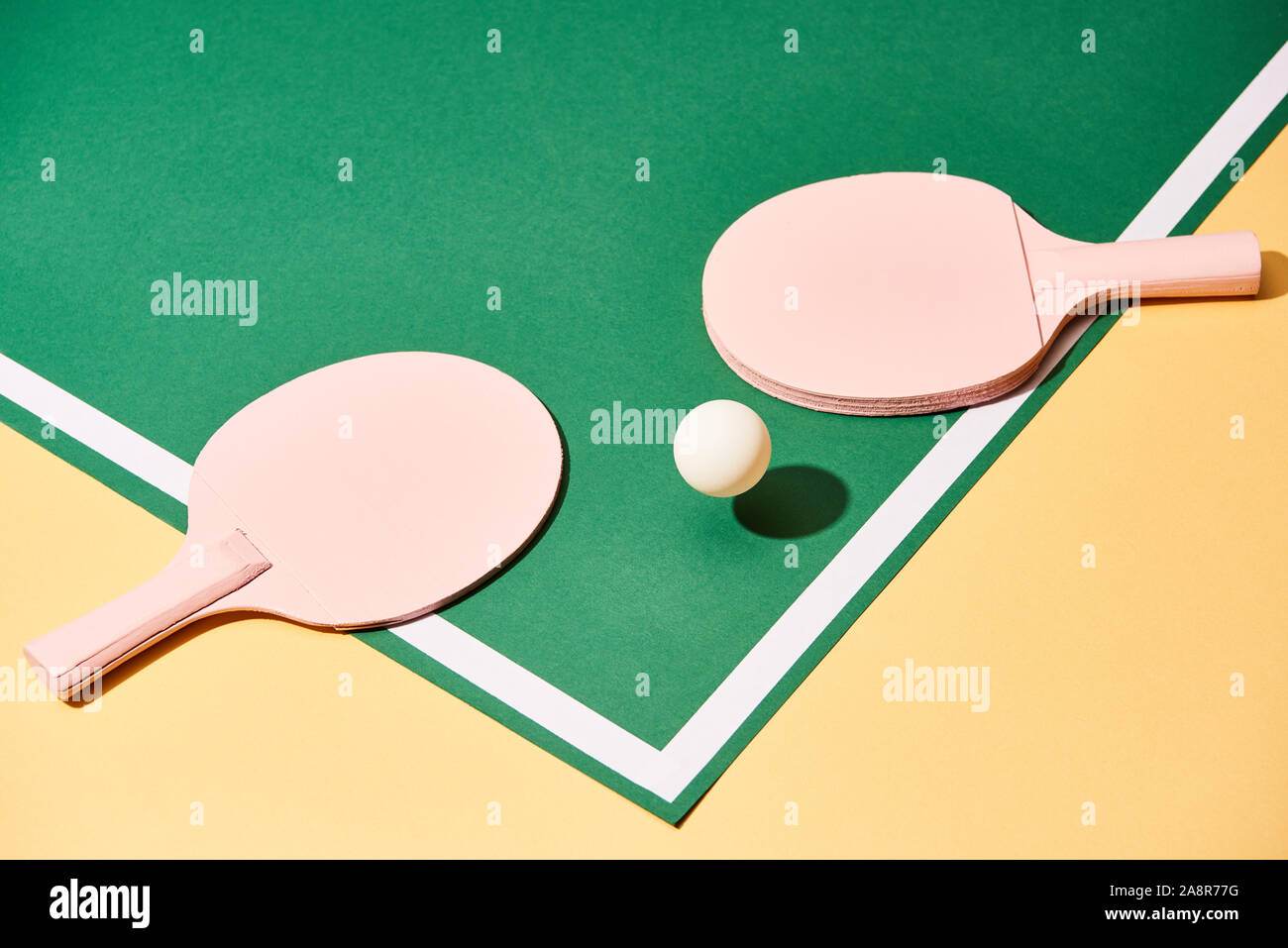 Wooden rackets and ball for table tennis on green and yellow surface ...