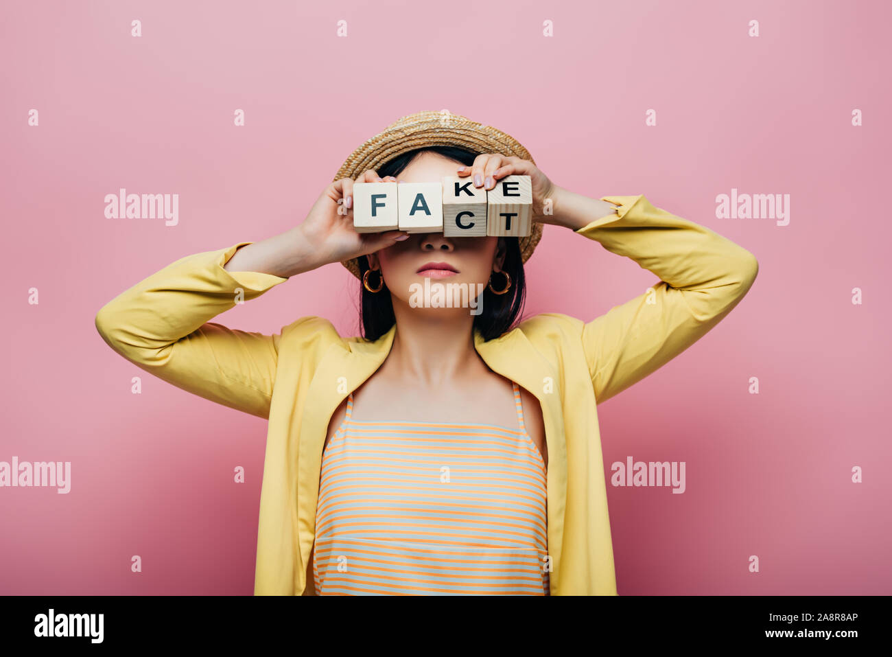 asian woman holding wooden cubes in front of face with fake and fact ...