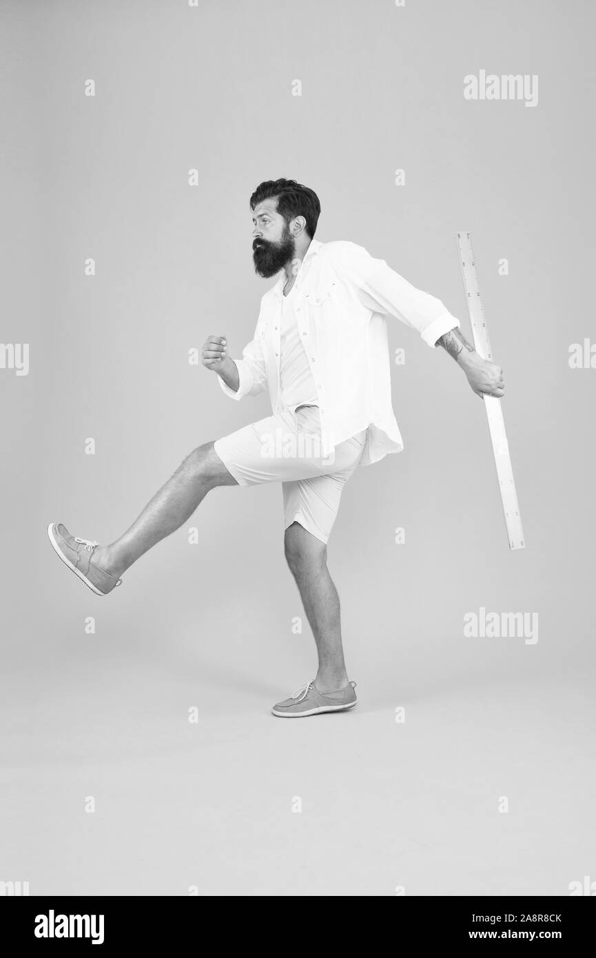 Knowledge in brutal world. Brutal hipster walking with ruler on yellow ...