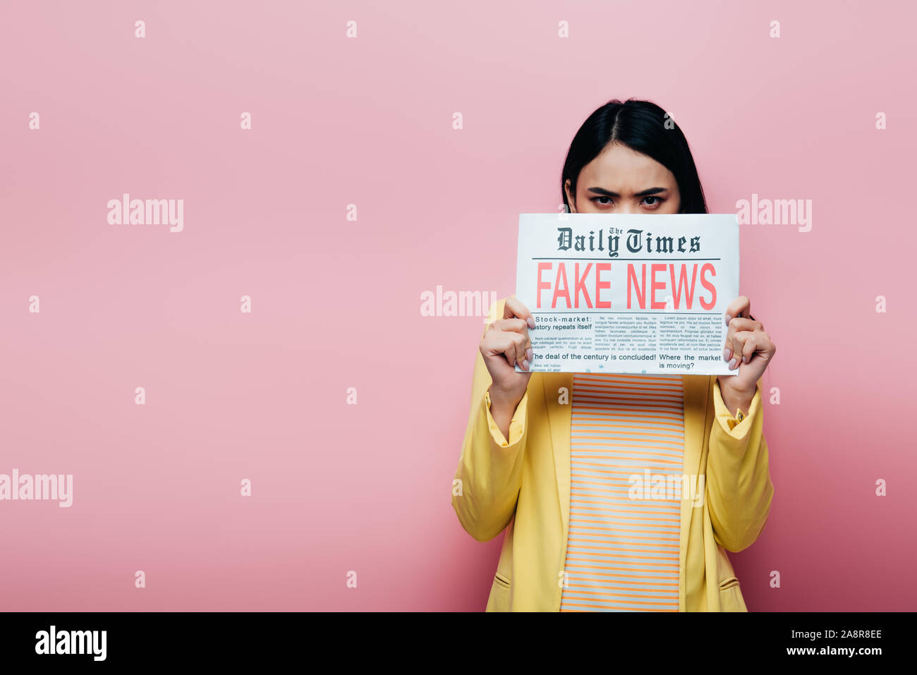 sad asian woman in yellow outfit holding newspaper with fake news ...