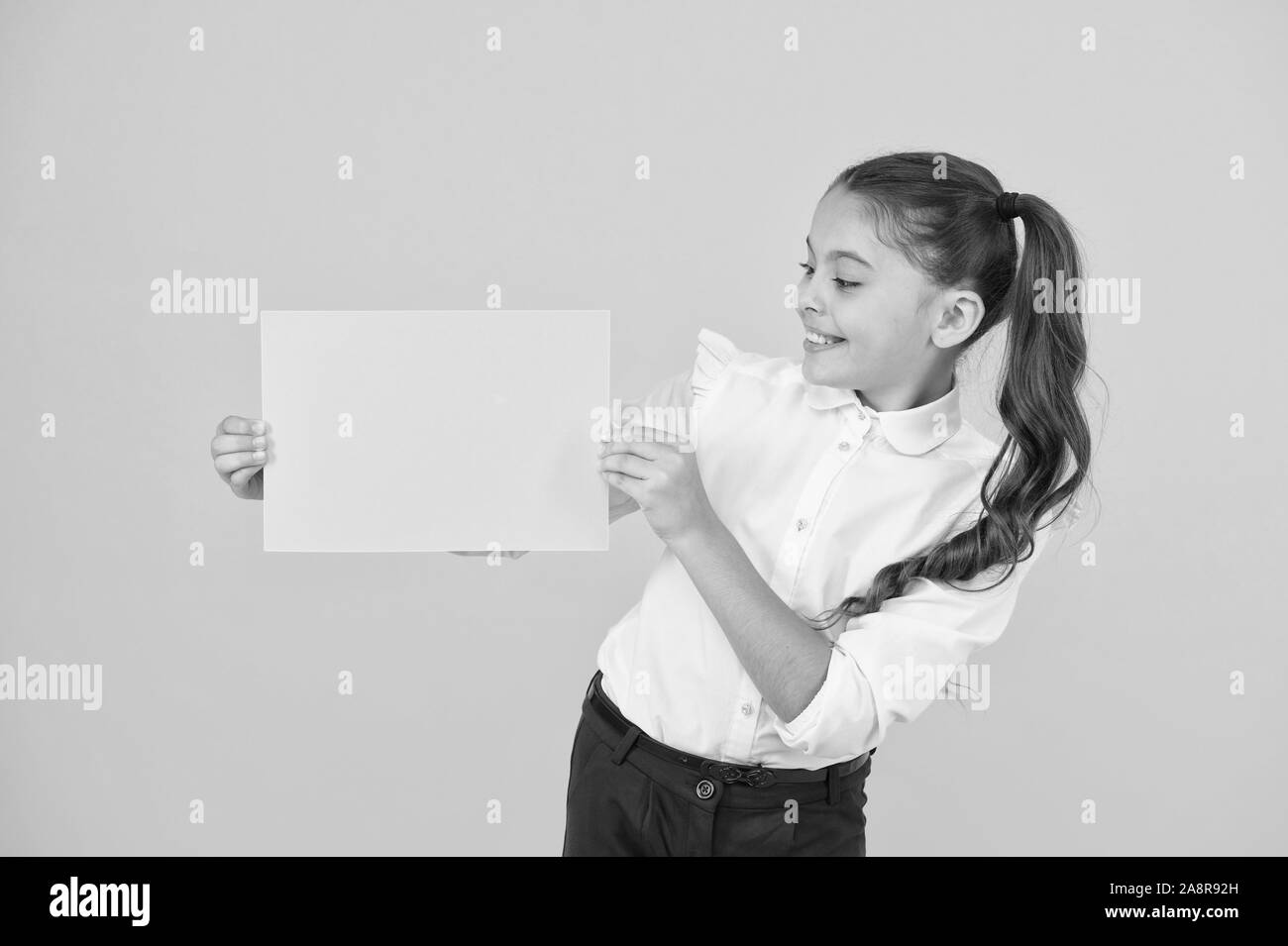 Glorious colour. Little girl holding empty sheet of paper on yellow ...