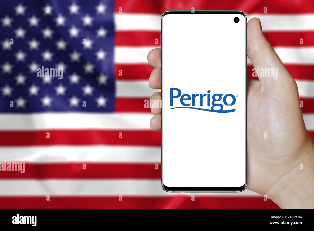 Logo of public company Perrigo displayed on a smartphone. Flag of USA ...