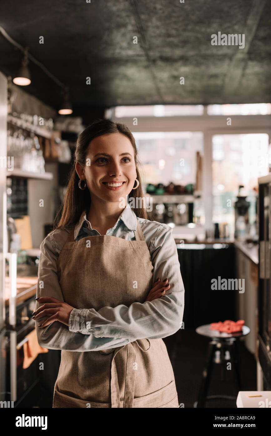 smiling barista in apron standing in cafe with crossed arms Stock Photo ...
