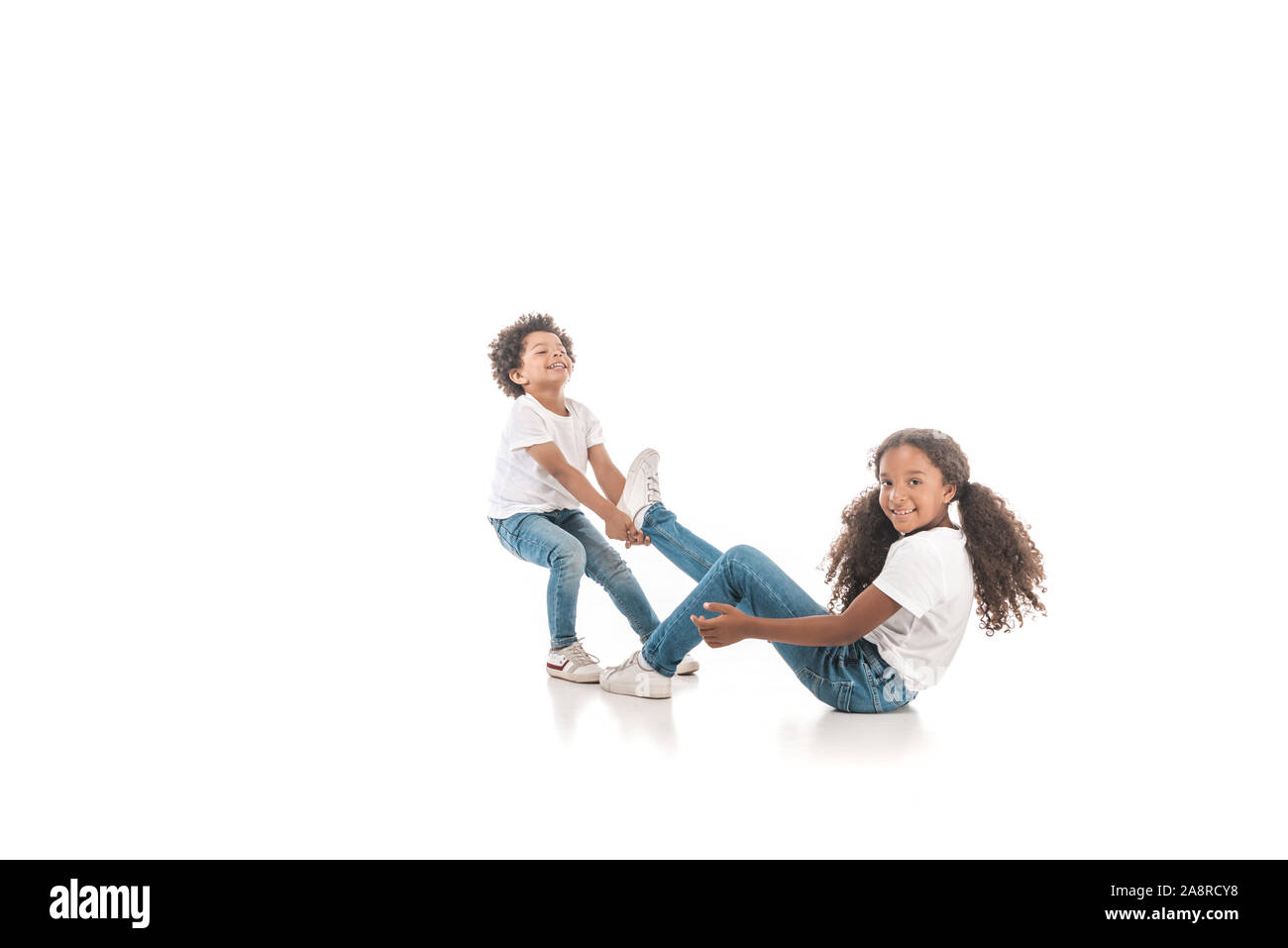 joyful african american boy dragging sister by leg on white background ...