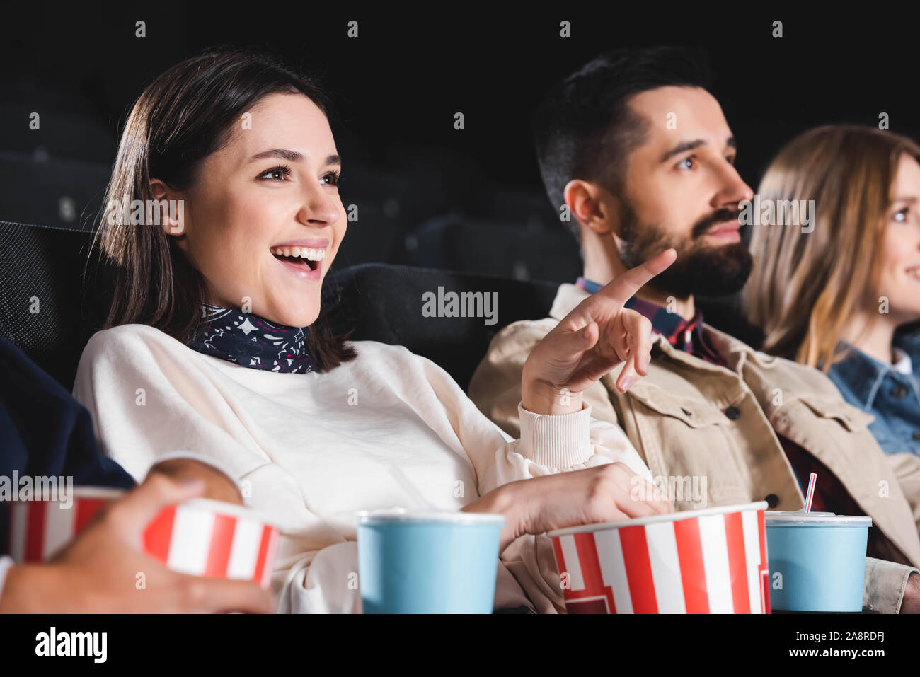 selective focus of smiling woman pointing with finger and watching ...