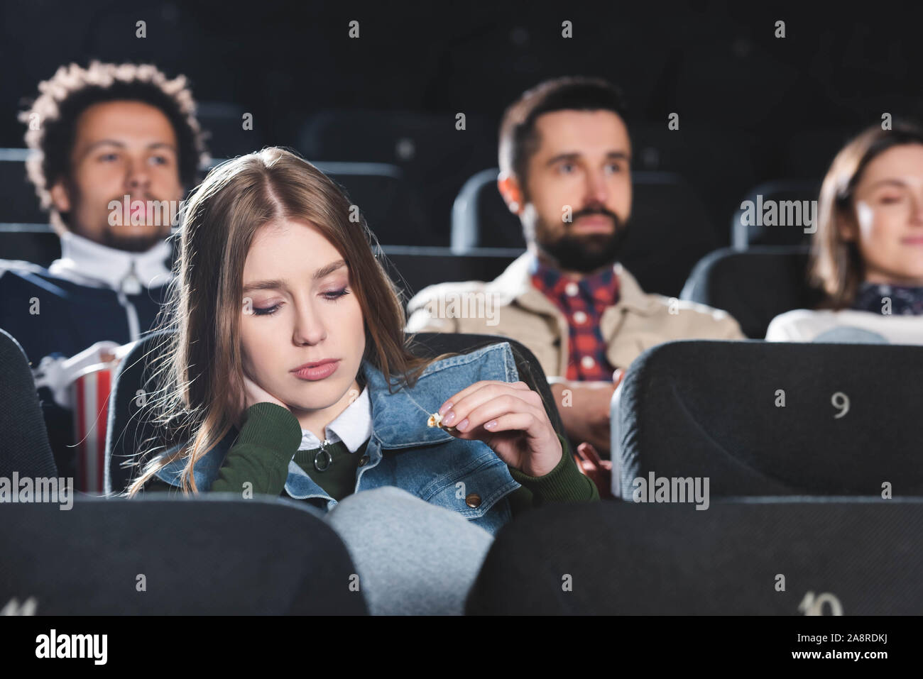 selective focus of sad woman looking down in cinema Stock Photo - Alamy