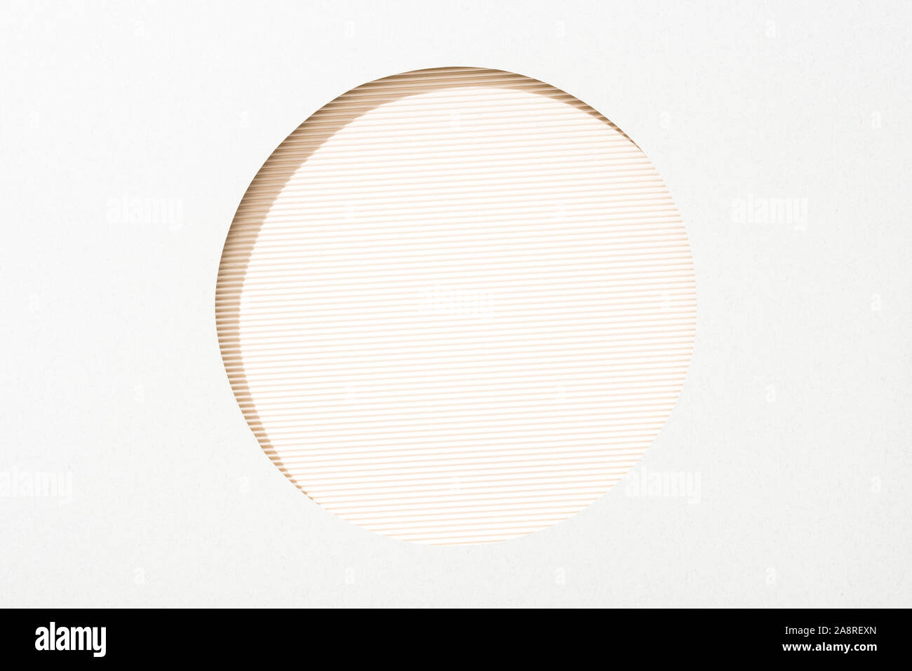 cut out round hole in white paper on beige striped colorful background ...