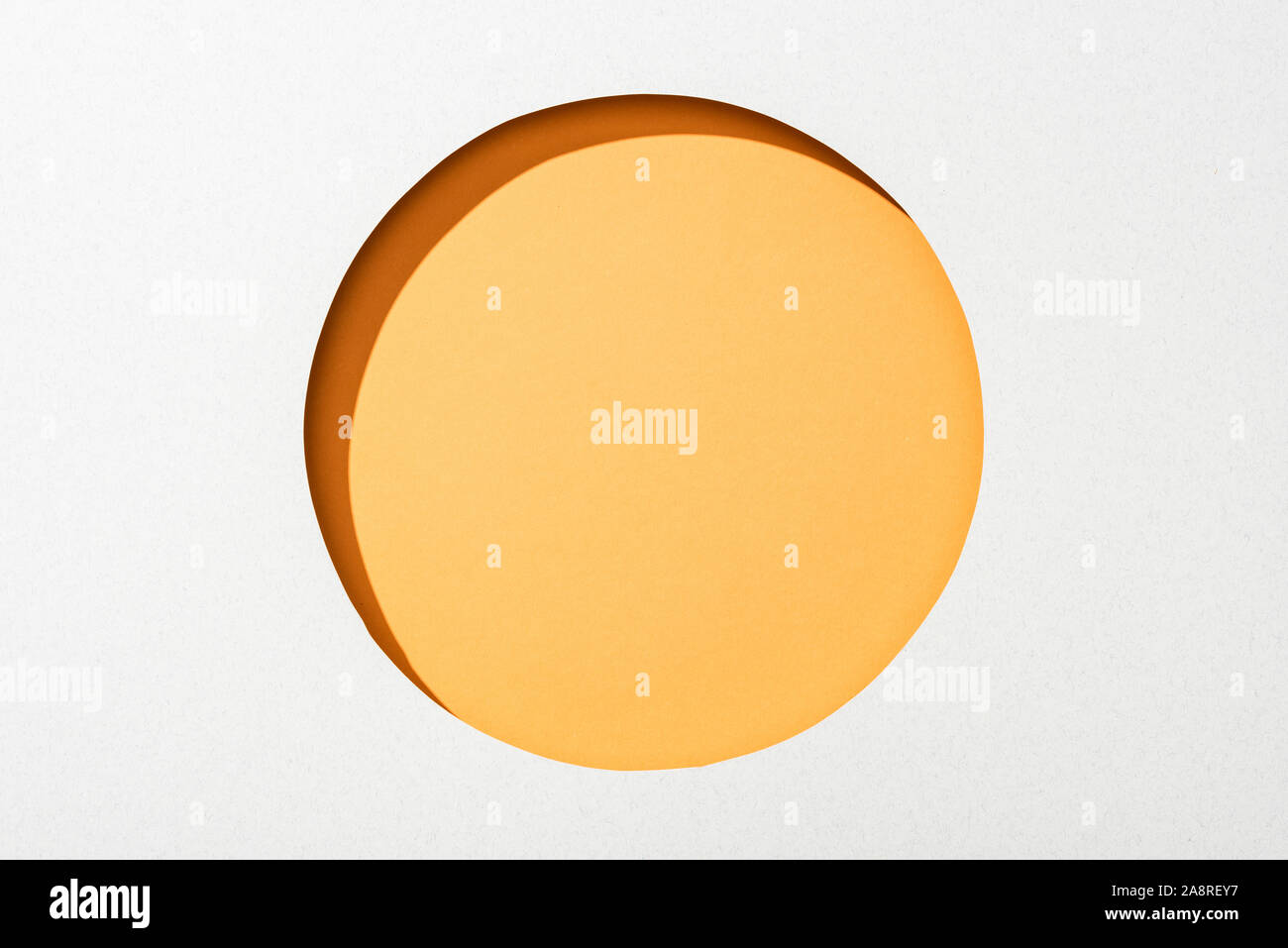 cut out round hole in white paper on orange background Stock Photo - Alamy