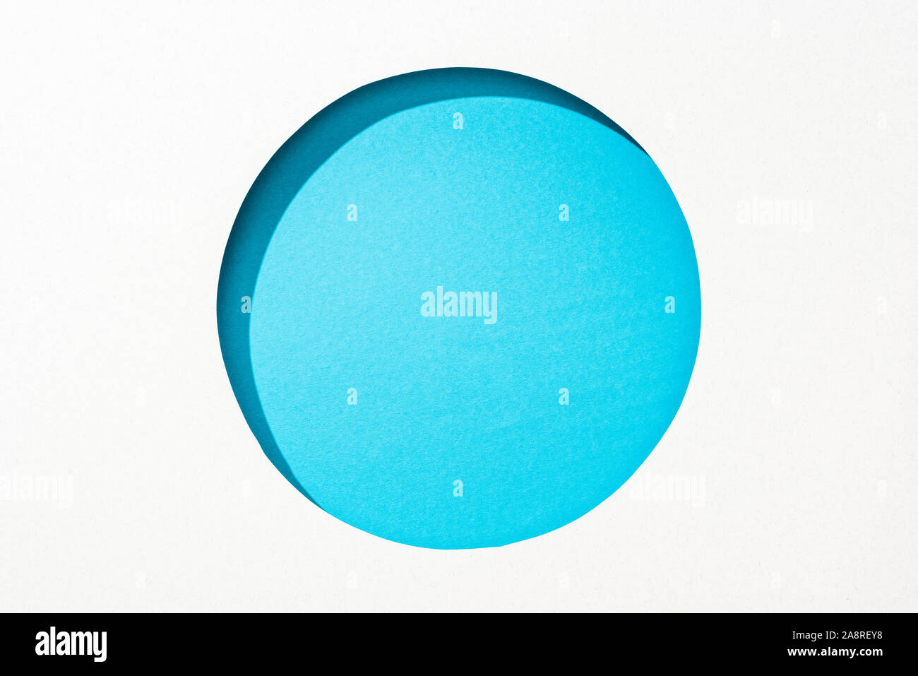 cut out round hole in white paper on blue background Stock Photo - Alamy