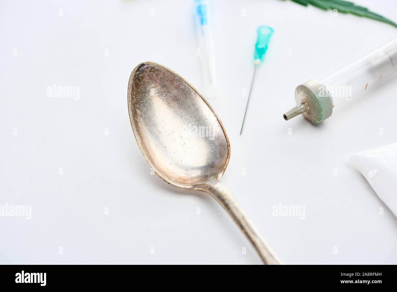 close up view of silver spoon, syringe and needles on white background ...