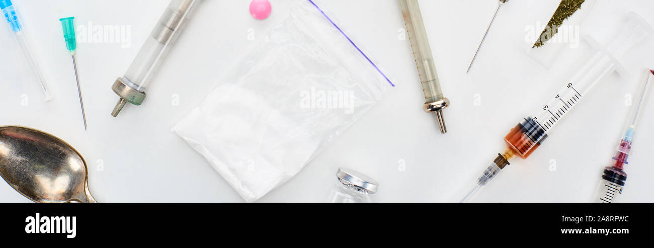 top view of marijuana, syringes with heroin, lsd and spoon on white ...