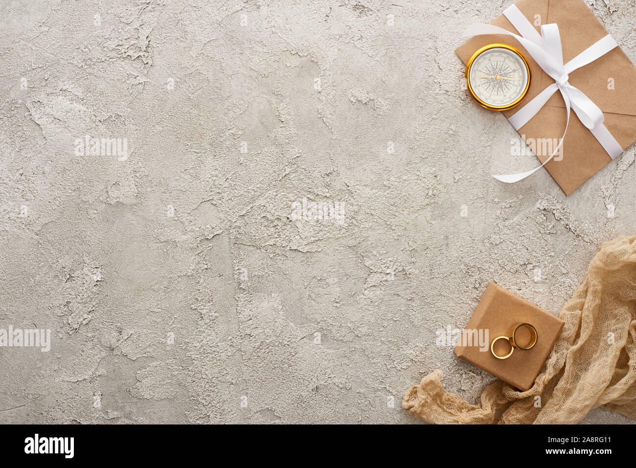 top view of golden compass, beige sackcloth, golden rings on gift box ...