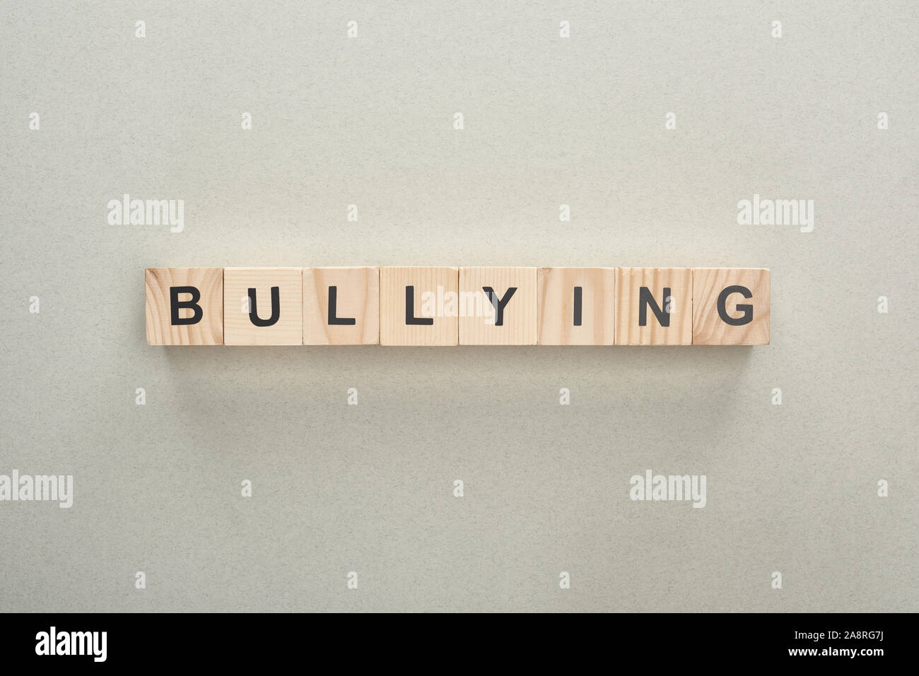 top view of wooden blocks with bullying lettering on grey background ...