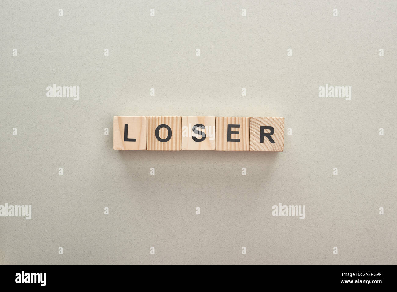 top view of wooden blocks with loser word on grey background, bullying ...