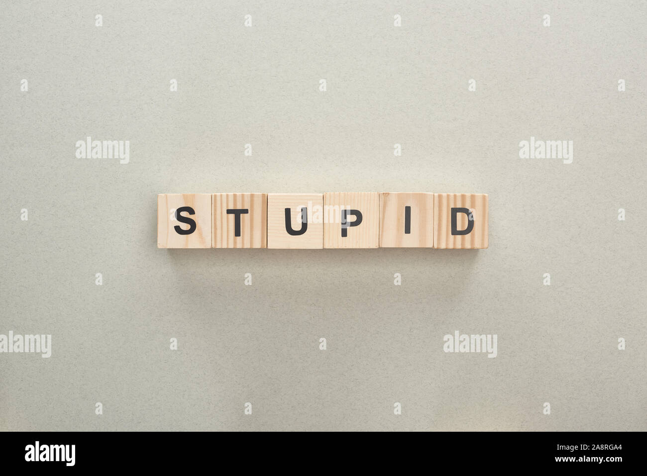 top view of wooden blocks with stupid lettering on grey background ...
