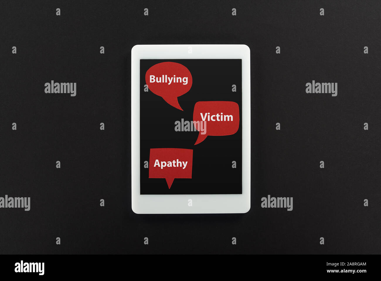 top view of digital tablet and red speech bubbles with bullying, victim ...