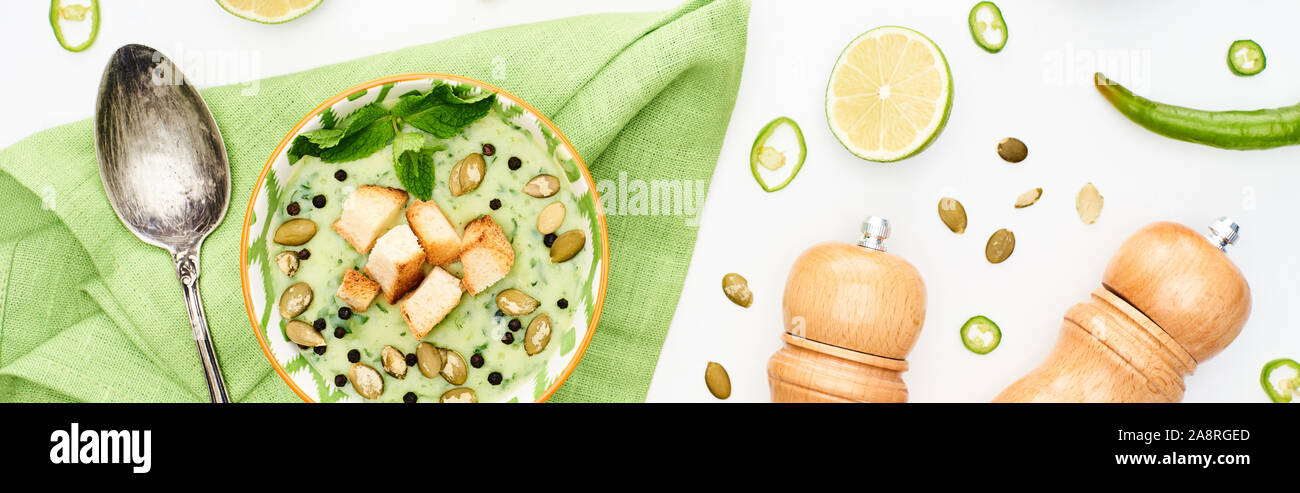 top view of delicious creamy green vegetable soup near pepper and salt ...