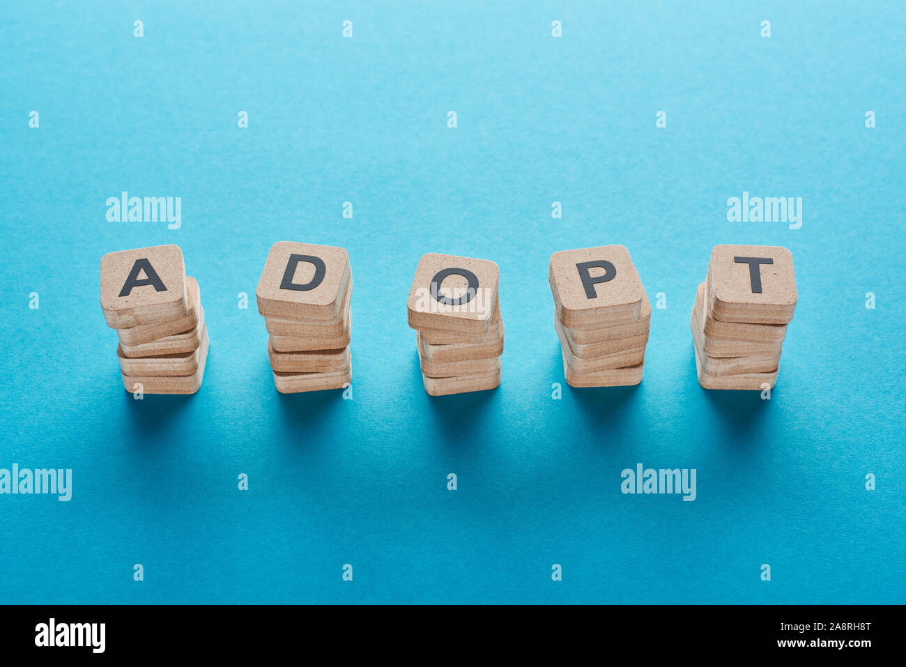 wooden blocks with adopt lettering on blue background Stock Photo - Alamy