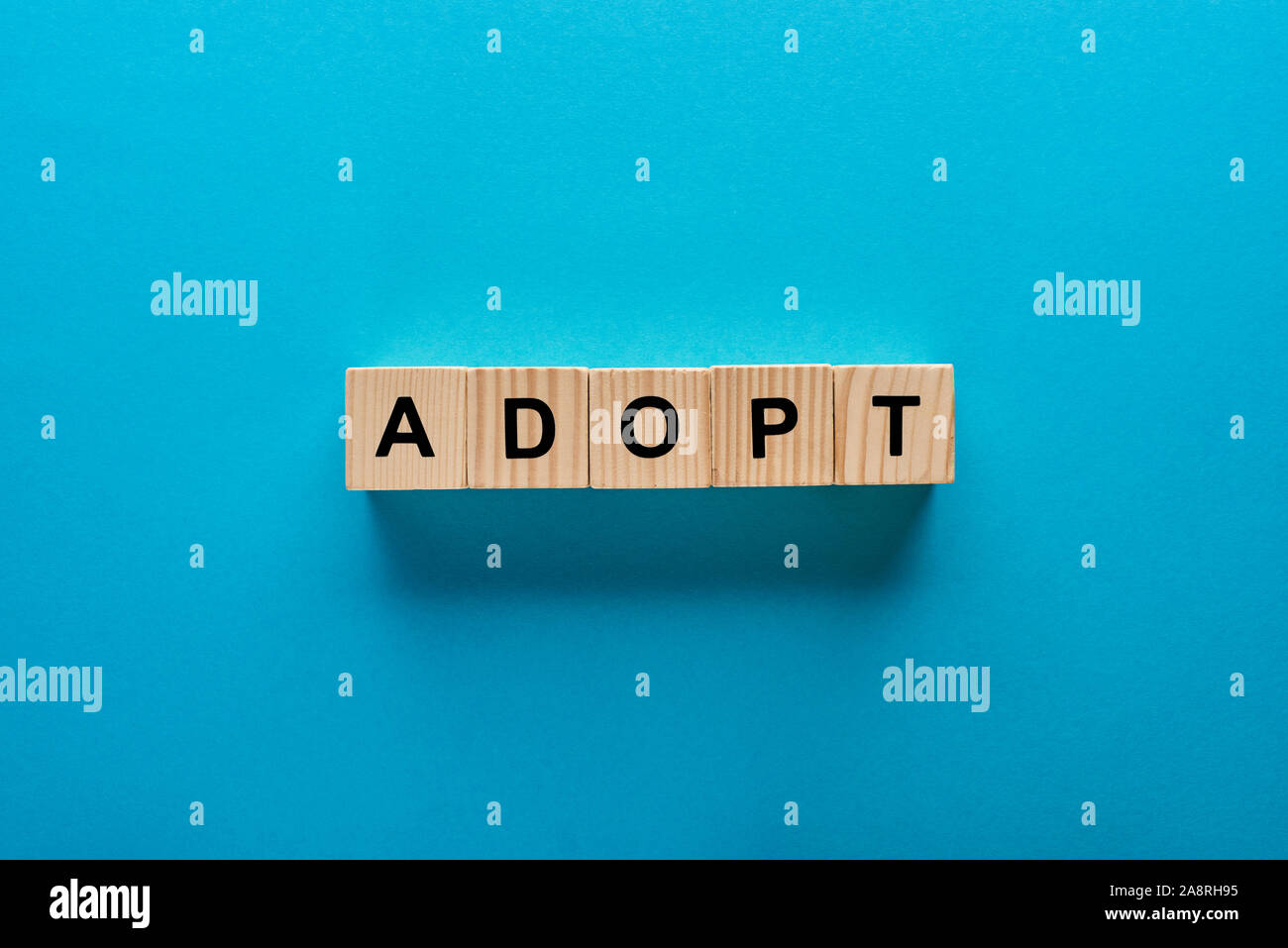 top view of wooden blocks with adopt word on blue background Stock ...