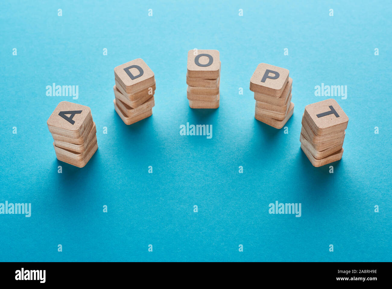 wooden blocks with adopt lettering on blue background with copy space ...