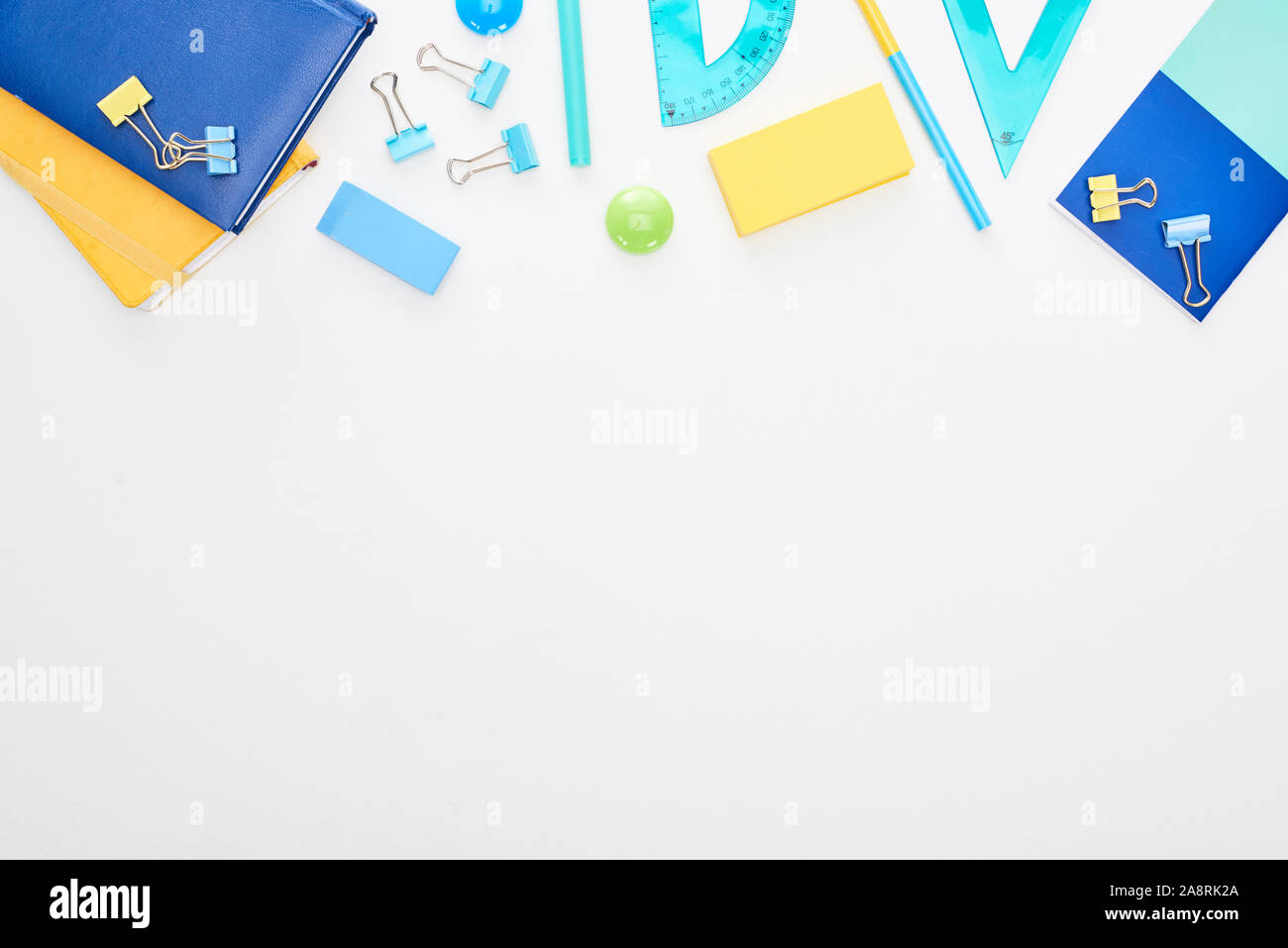 Top view of blue and yellow scattered school supplies with notepads ...