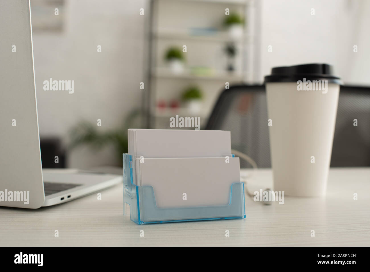 card holder with white blank business cards near paper cup and laptop ...