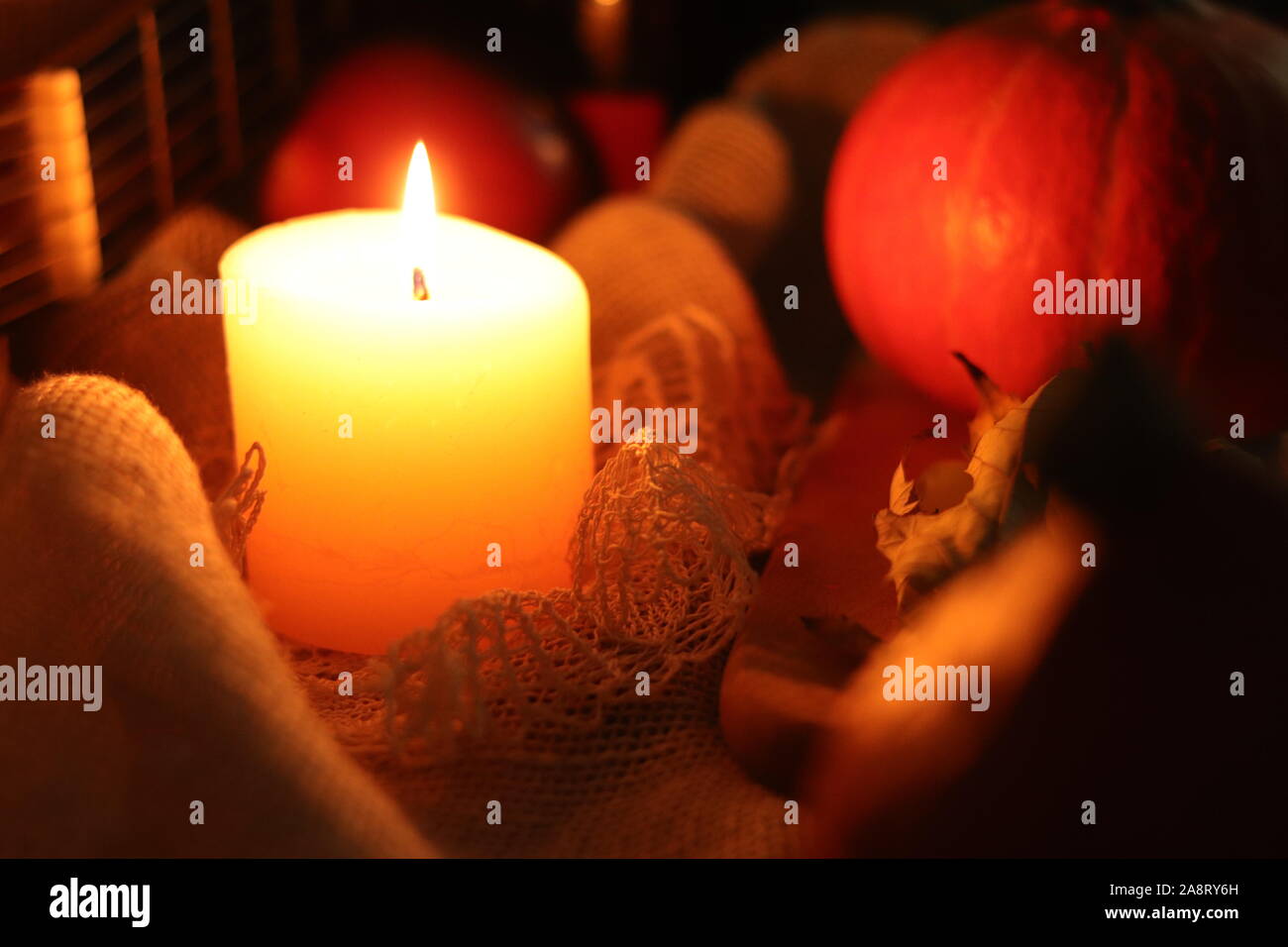 Fall warmth still life. Soft candle light with pumpkin and leaf on lace ...