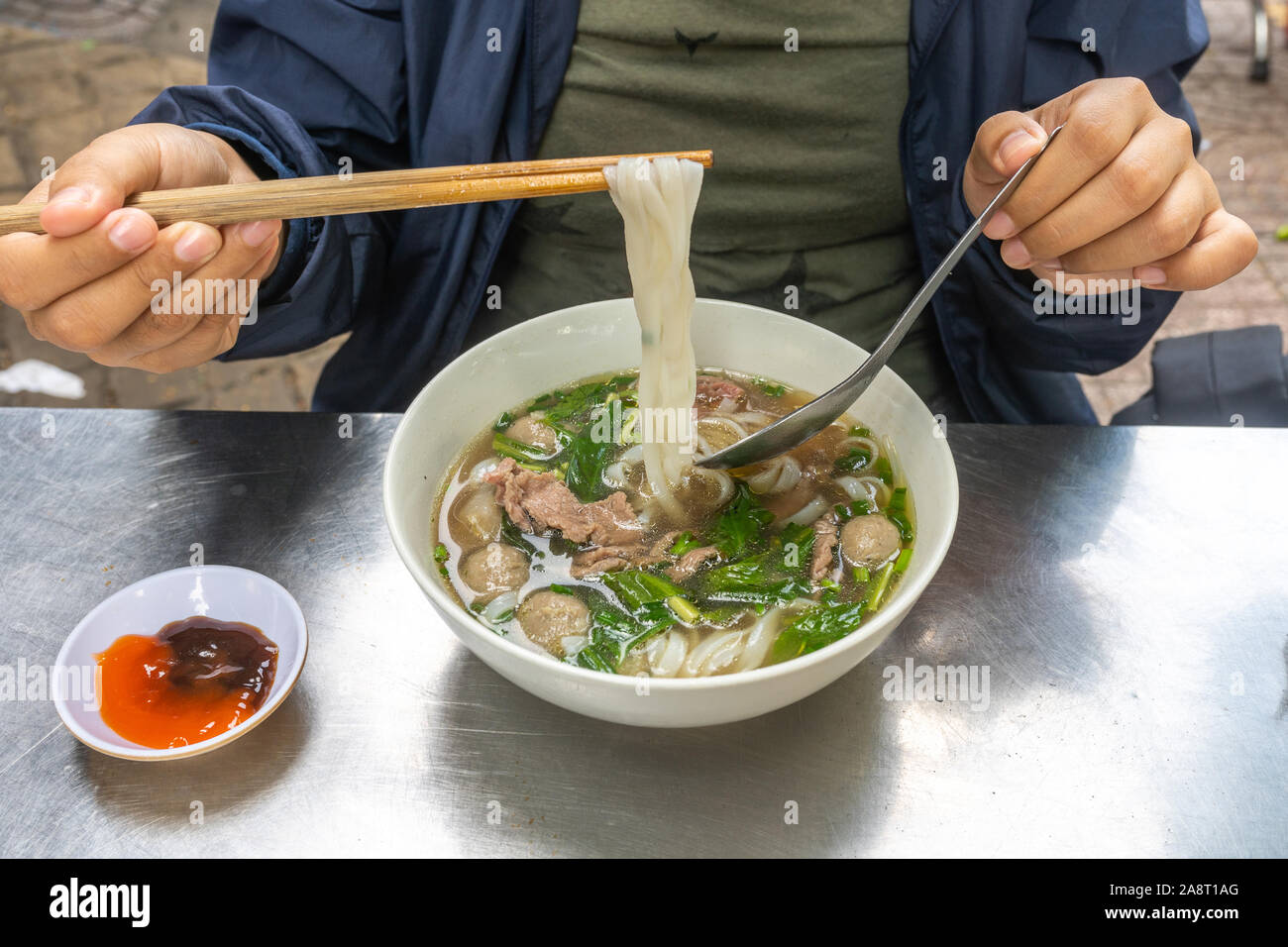 Human hand using chopsticks while having pho noodle soup Stock Photo ...