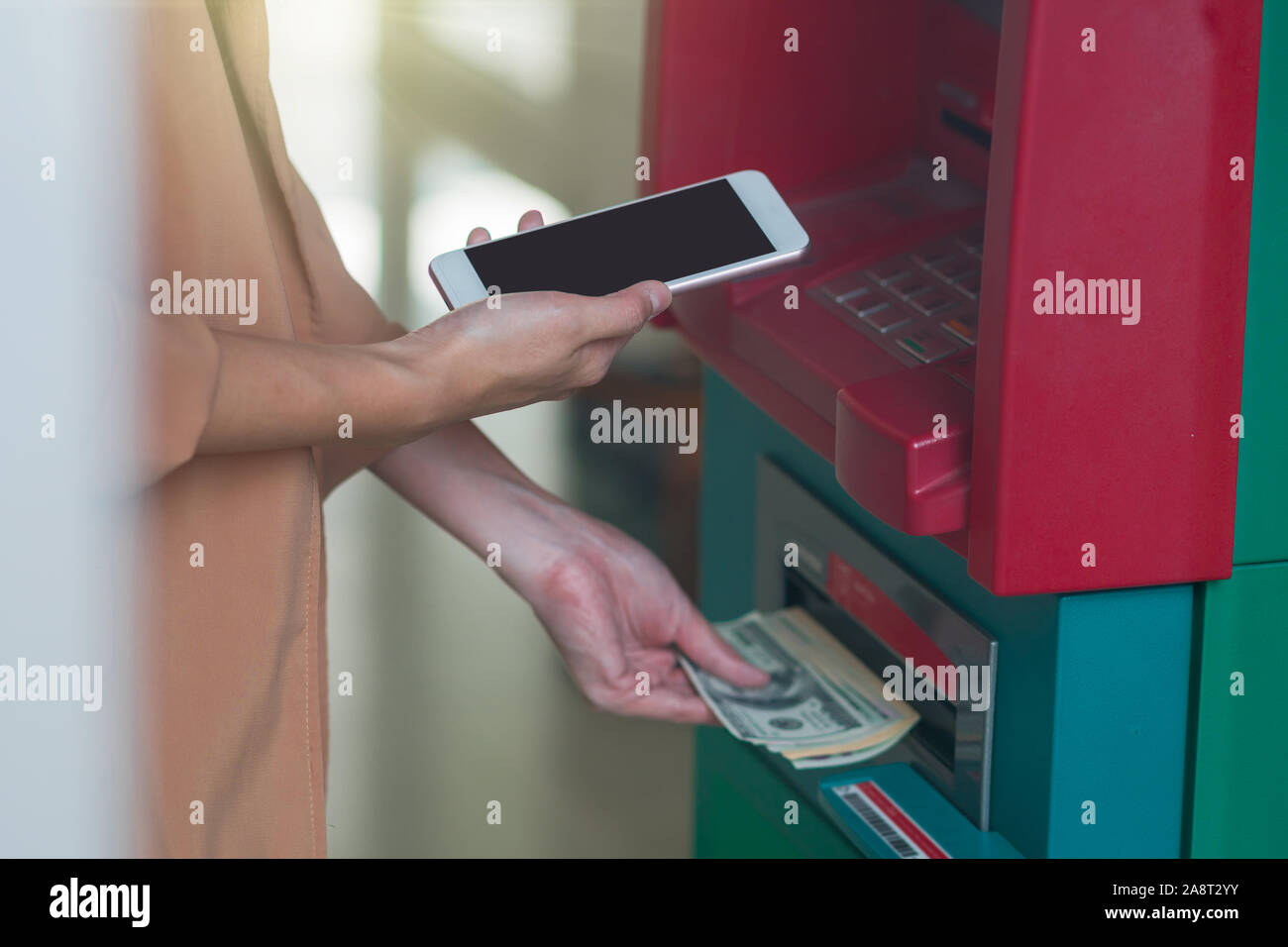 woman using the smart mobile phone for withdrawing in front of the ATM ...