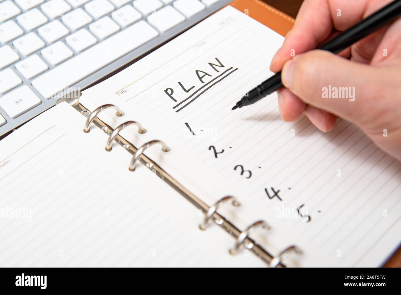 Close-up of a businessman's hand writing plan and list in the diary ...
