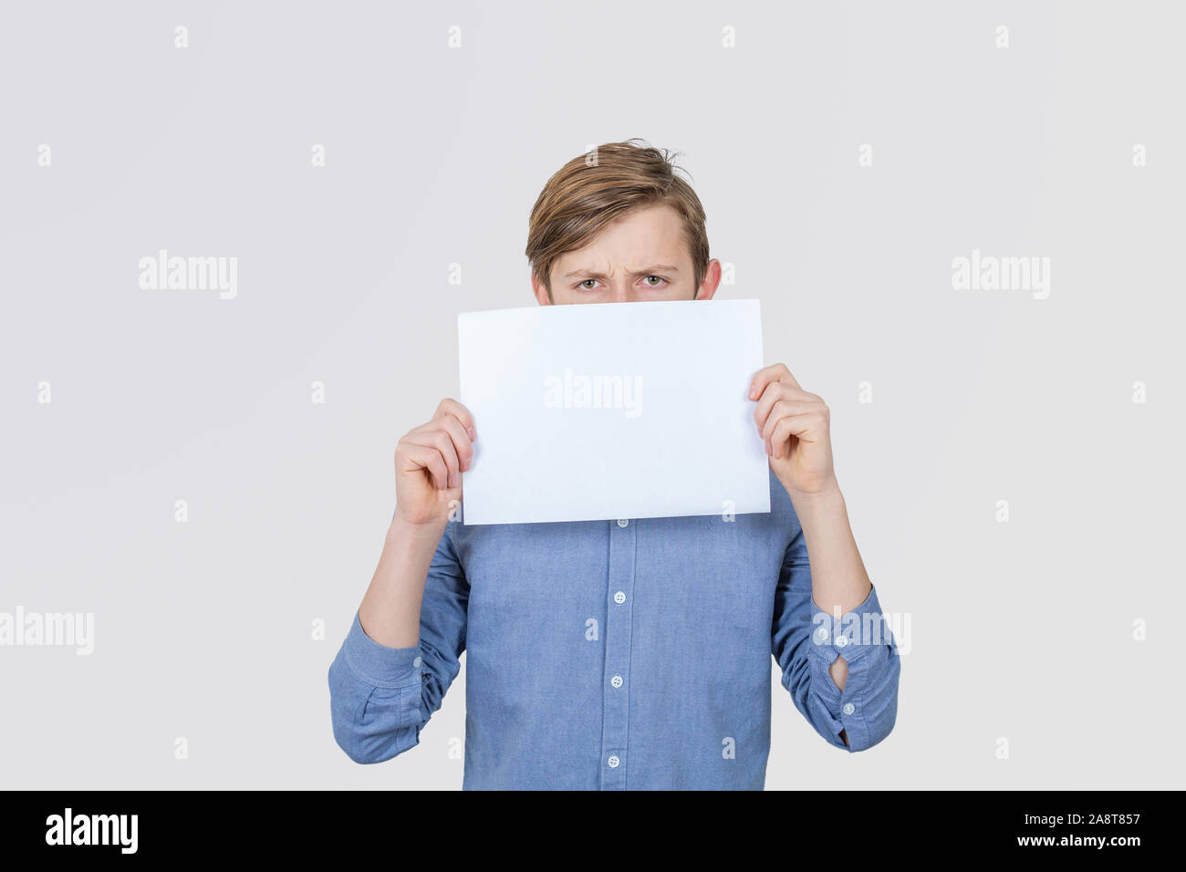 Serious Teenage boy holding blank sheet of paper covering half face ...