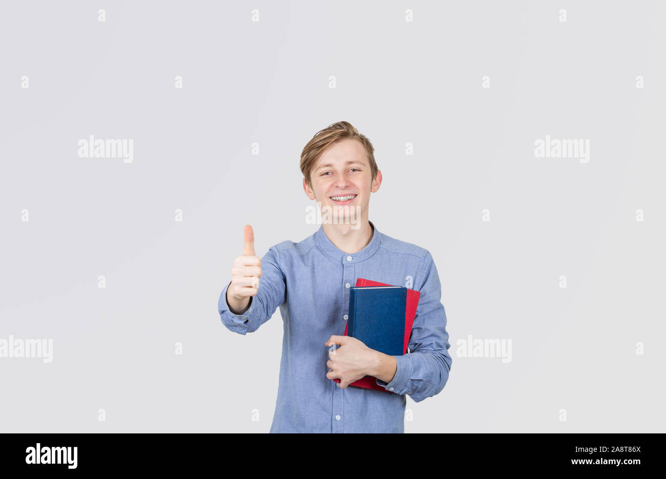Happy teenager boy smiling thumb up gesture holding books. Book lover ...