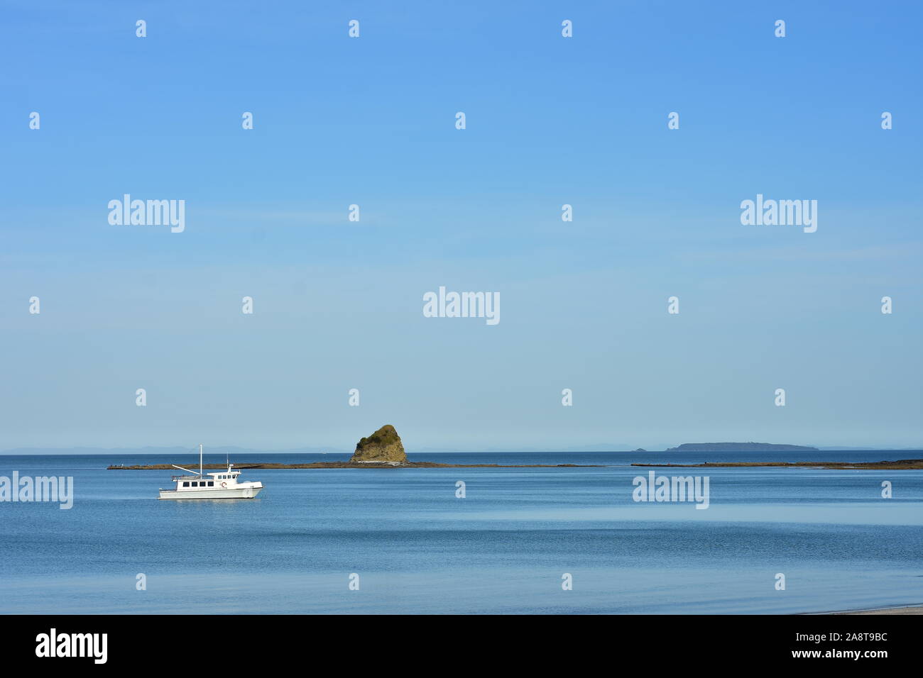 Wooden cabin motor boat painted white on flat calm sea surface near ...
