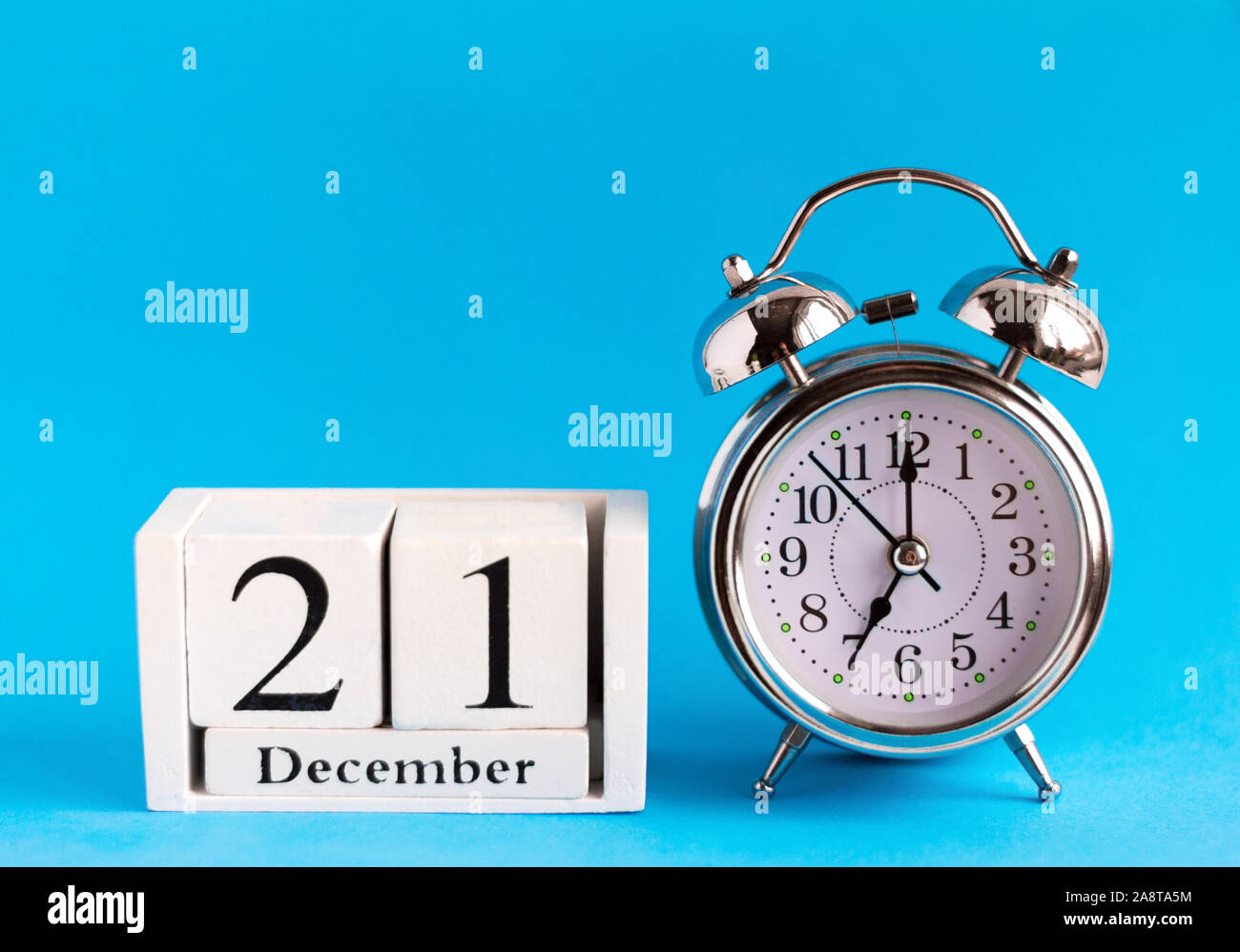 Calendar of white wooden cubes and alarm clock on a blue background ...