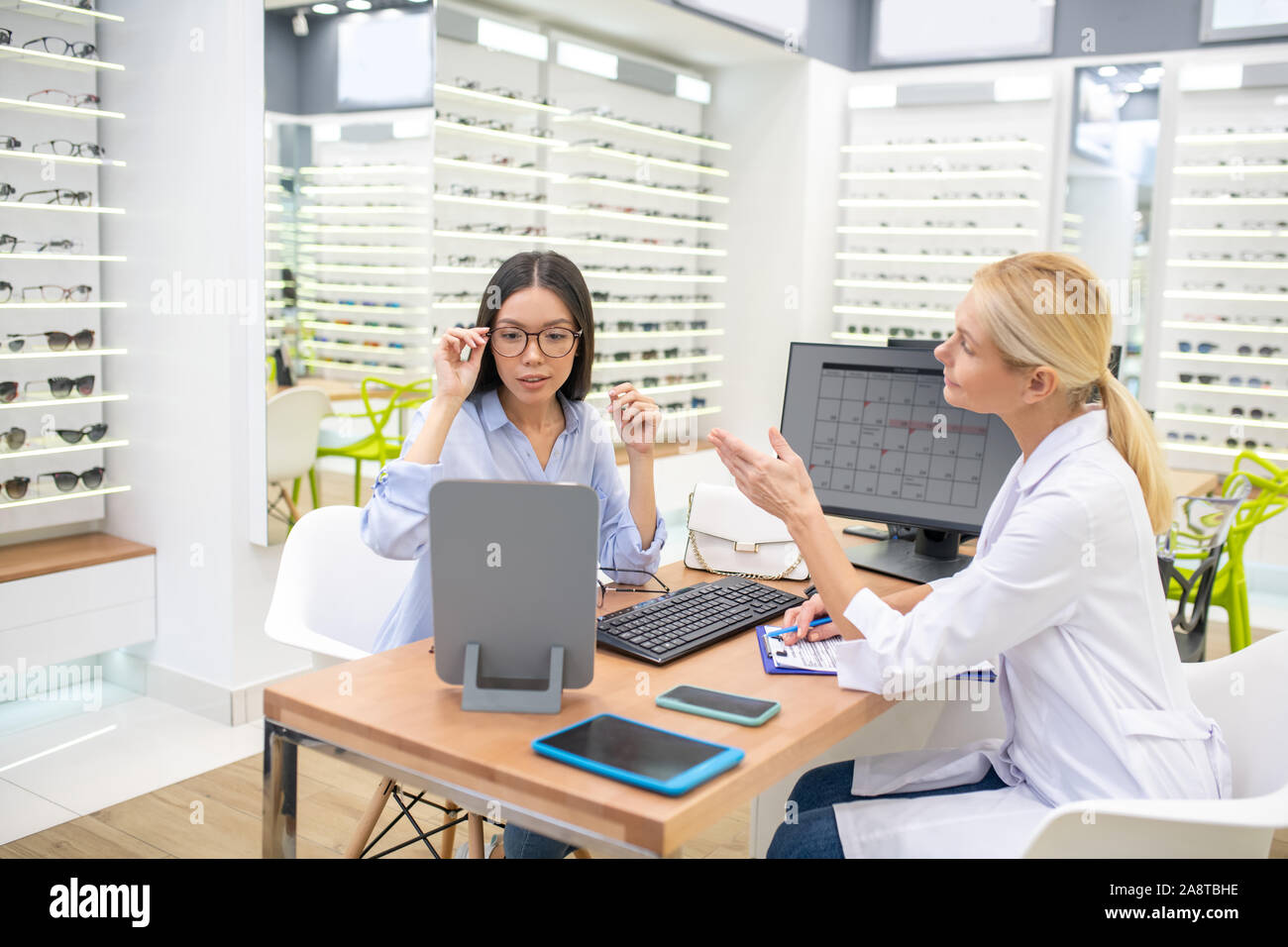 Dark-haired client trying glasses on after visual control Stock Photo ...