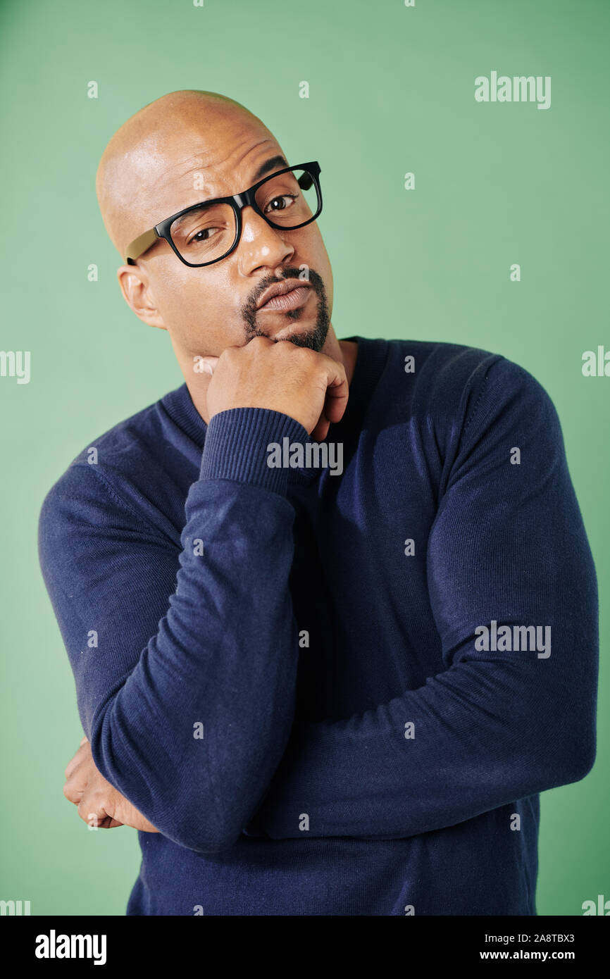 Portrait of intelligent muscular man in glasses thinking and looking at ...