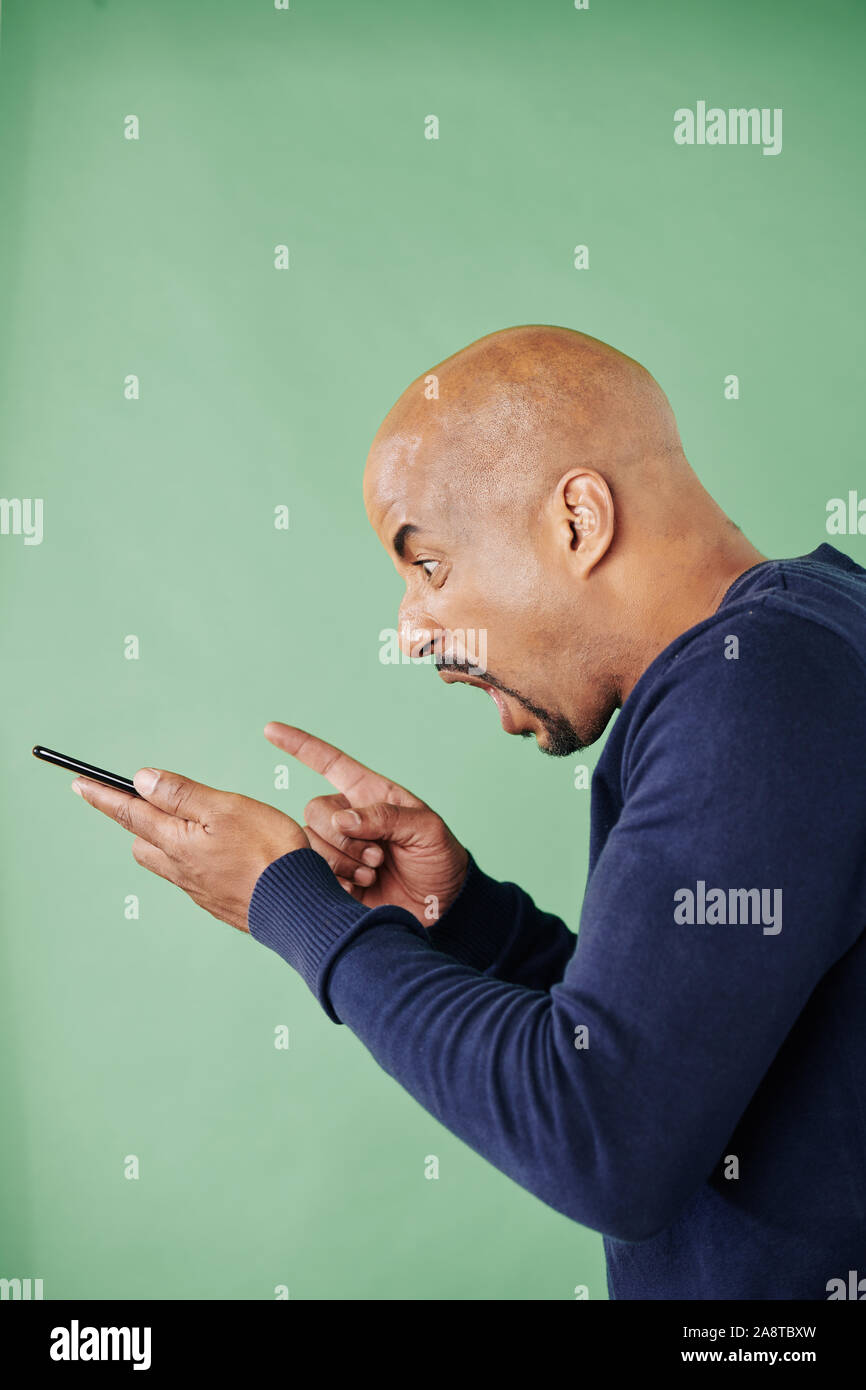 Angry man shouting at smartphone in his hand when recording voice ...
