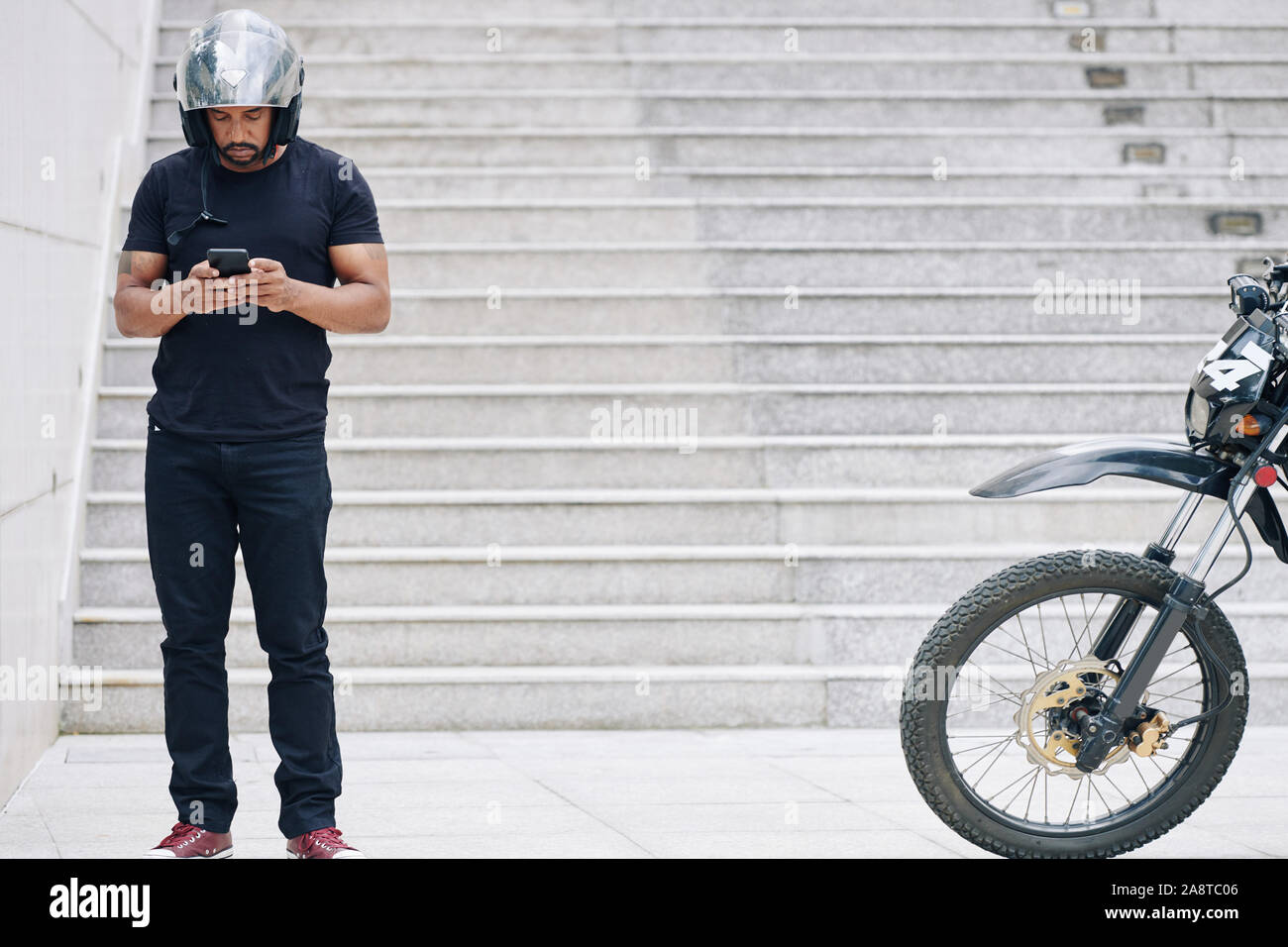 Man in motorcycle helmet standing outdoors and texting friends Stock ...