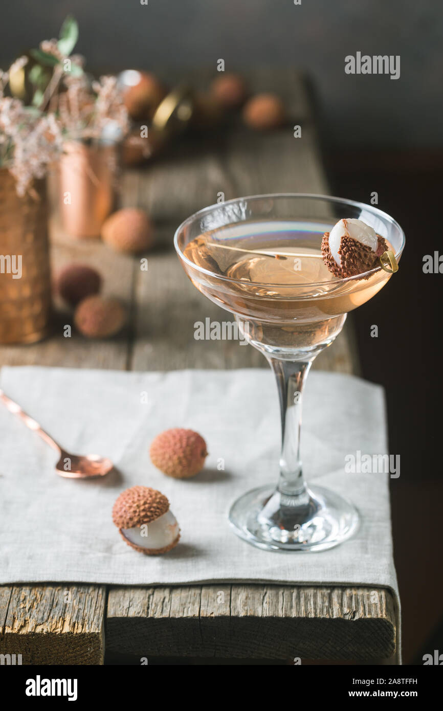 Glass of cold lychee cocktail on the old wooden table, rustic style ...
