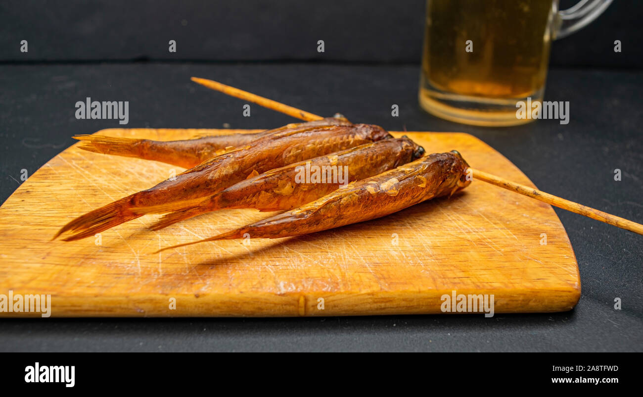 Dried mullet on a wooden Board with a mug of beer on the table. Fish ...