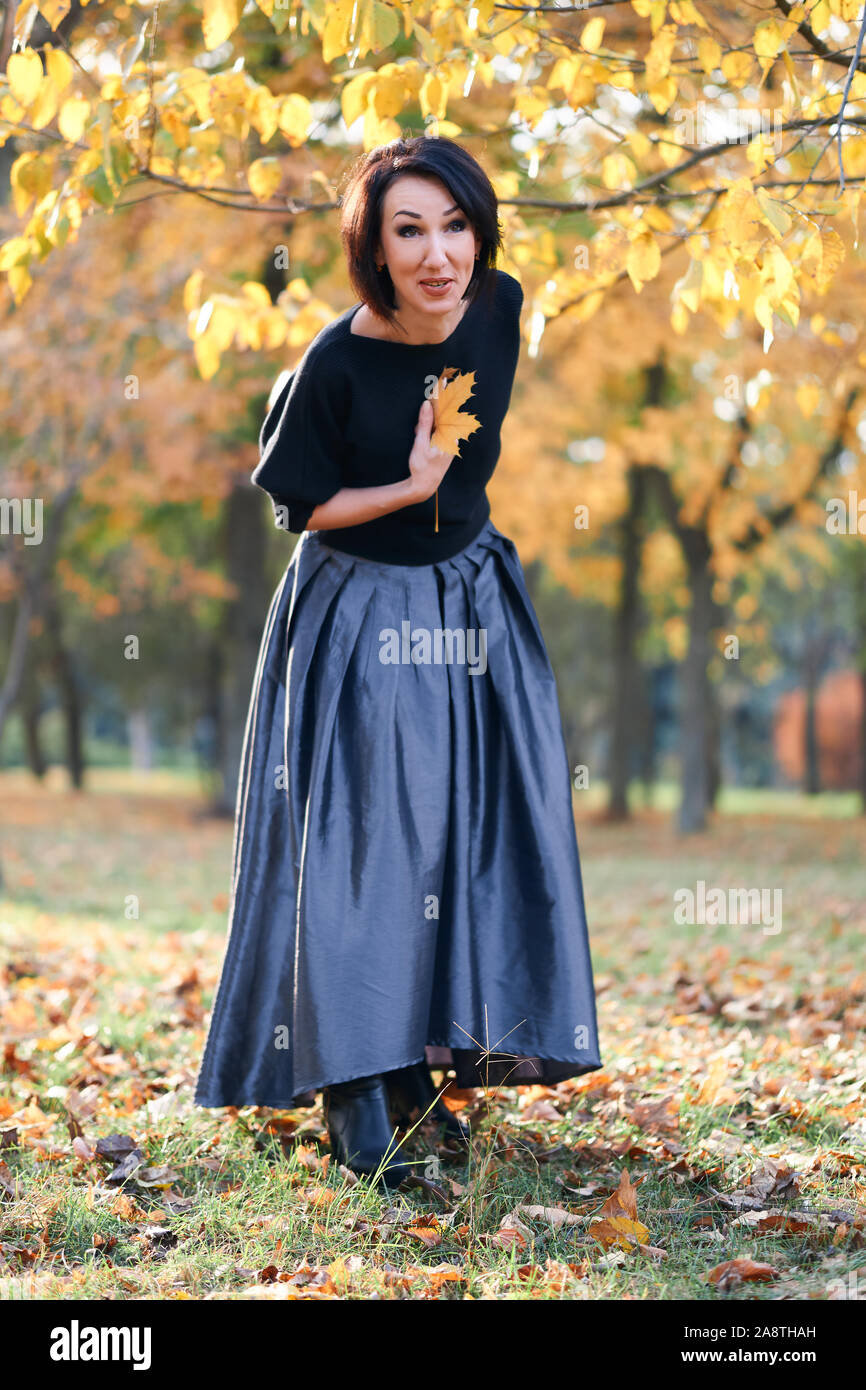 Beautiful elegant woman standing and posing in a city park in autumn ...